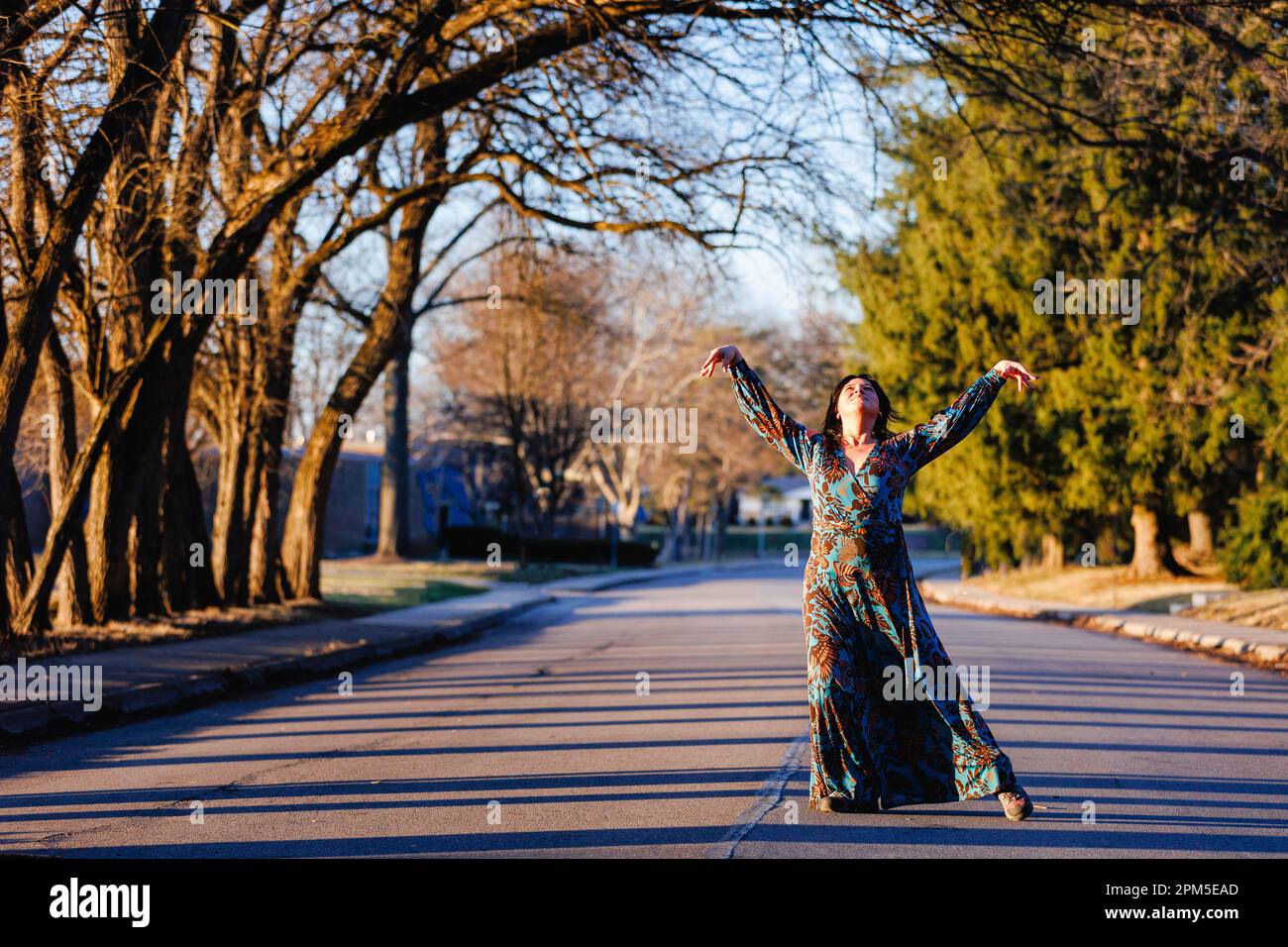 Woman stands in shadows on tree-lined street dancing Stock Photo - Alamy