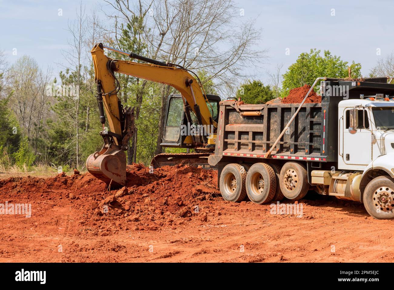 Earth is being loaded into dumper truck by an excavator Stock Photo - Alamy