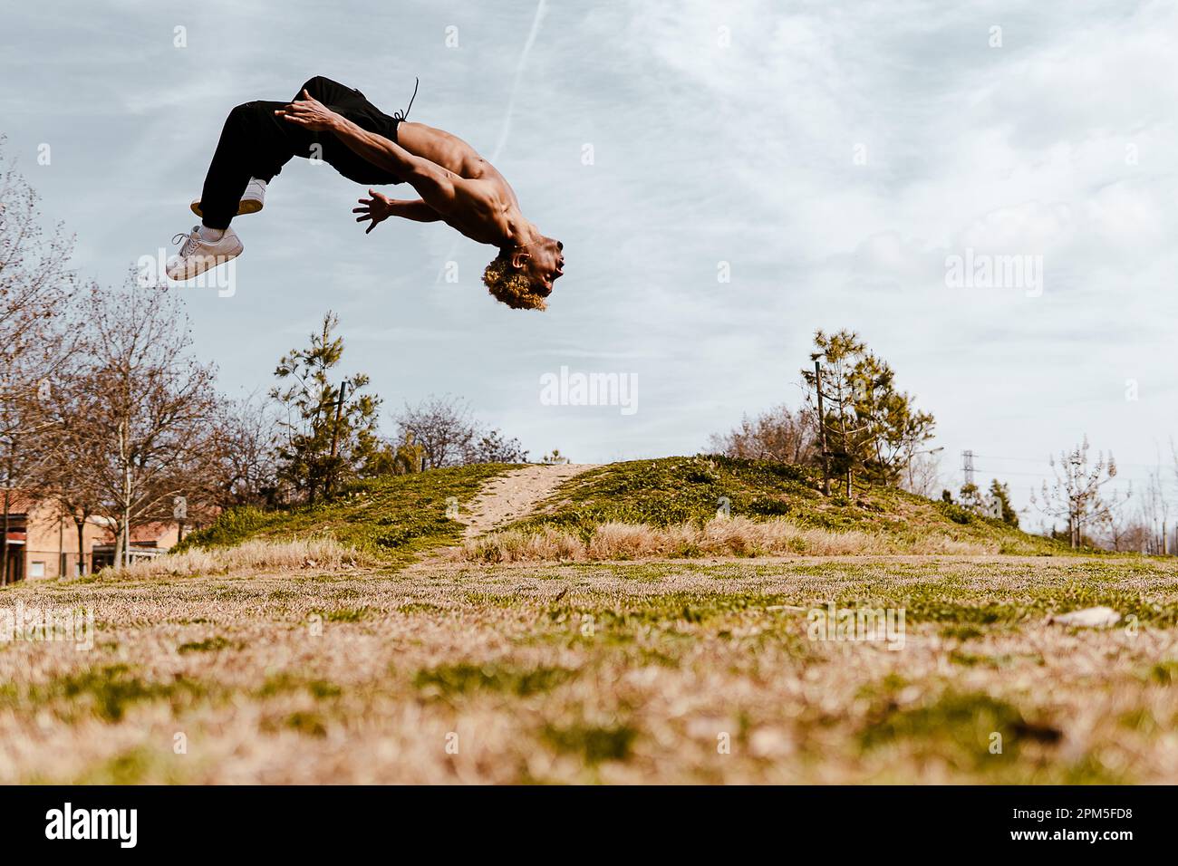 Stock photo of man doing somersault on field against clear sky Stock ...