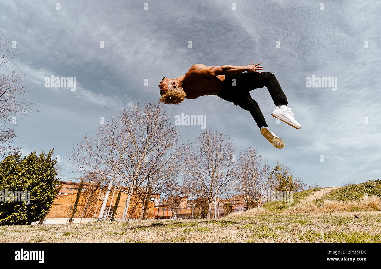 Stock photo of man doing somersault on field against clear sky Stock ...