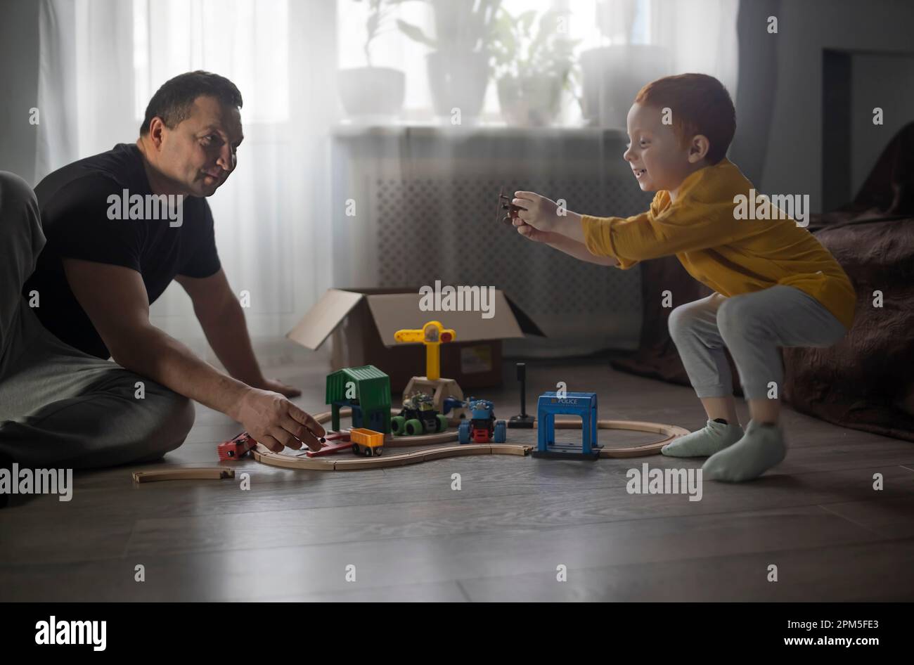 Dad and baby are playing with a wooden train track Stock Photo - Alamy