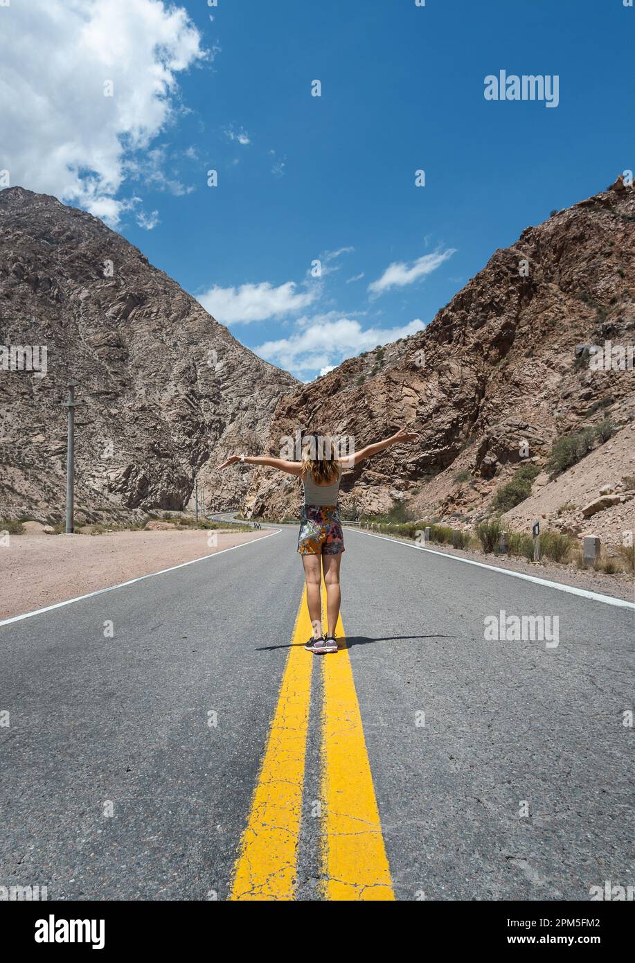 woman raising her arms on empty road between mountains Stock Photo - Alamy