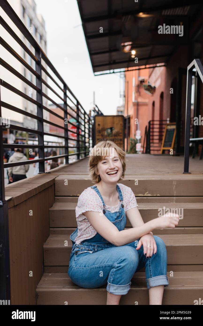 Happy woman sitting on outdoor steps looking at camera Stock Photo - Alamy
