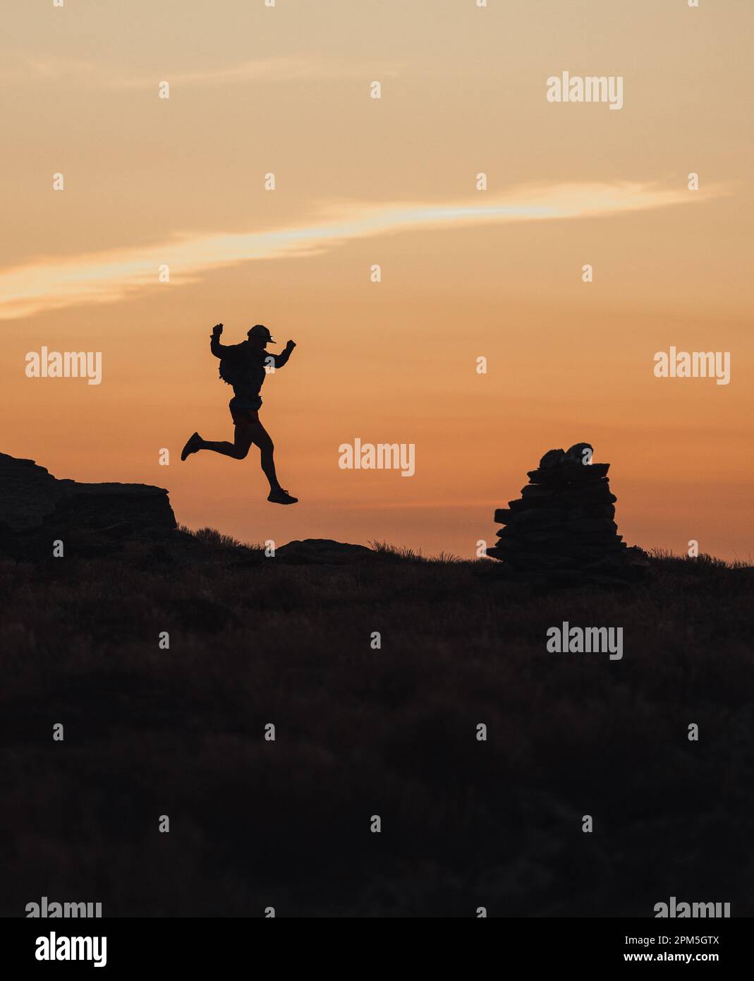 Silhouette male trail runner jumping off rock at dawn sunrise Stock ...