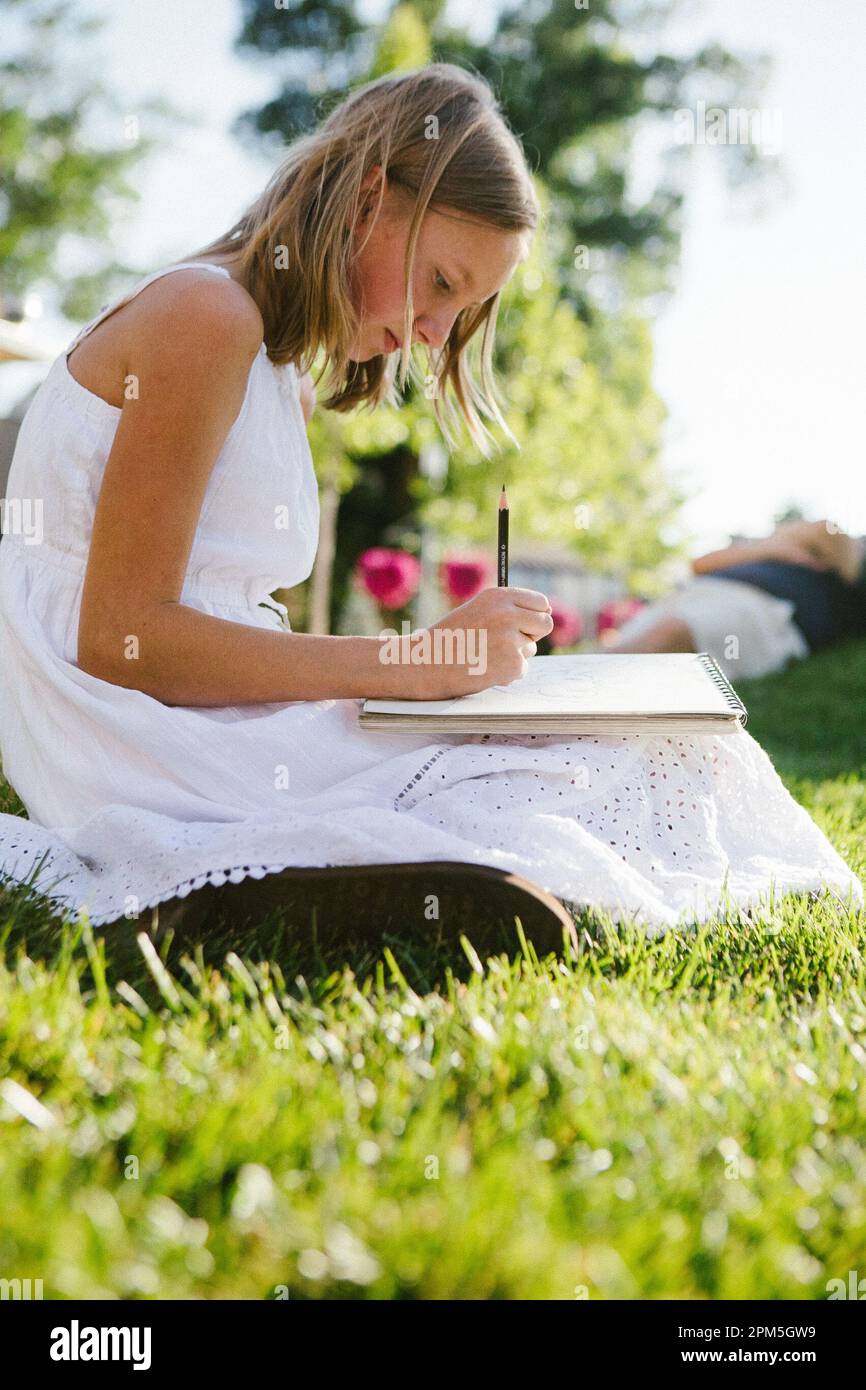 Girl drawing in lush green grass in mid summer outside Stock Photo - Alamy
