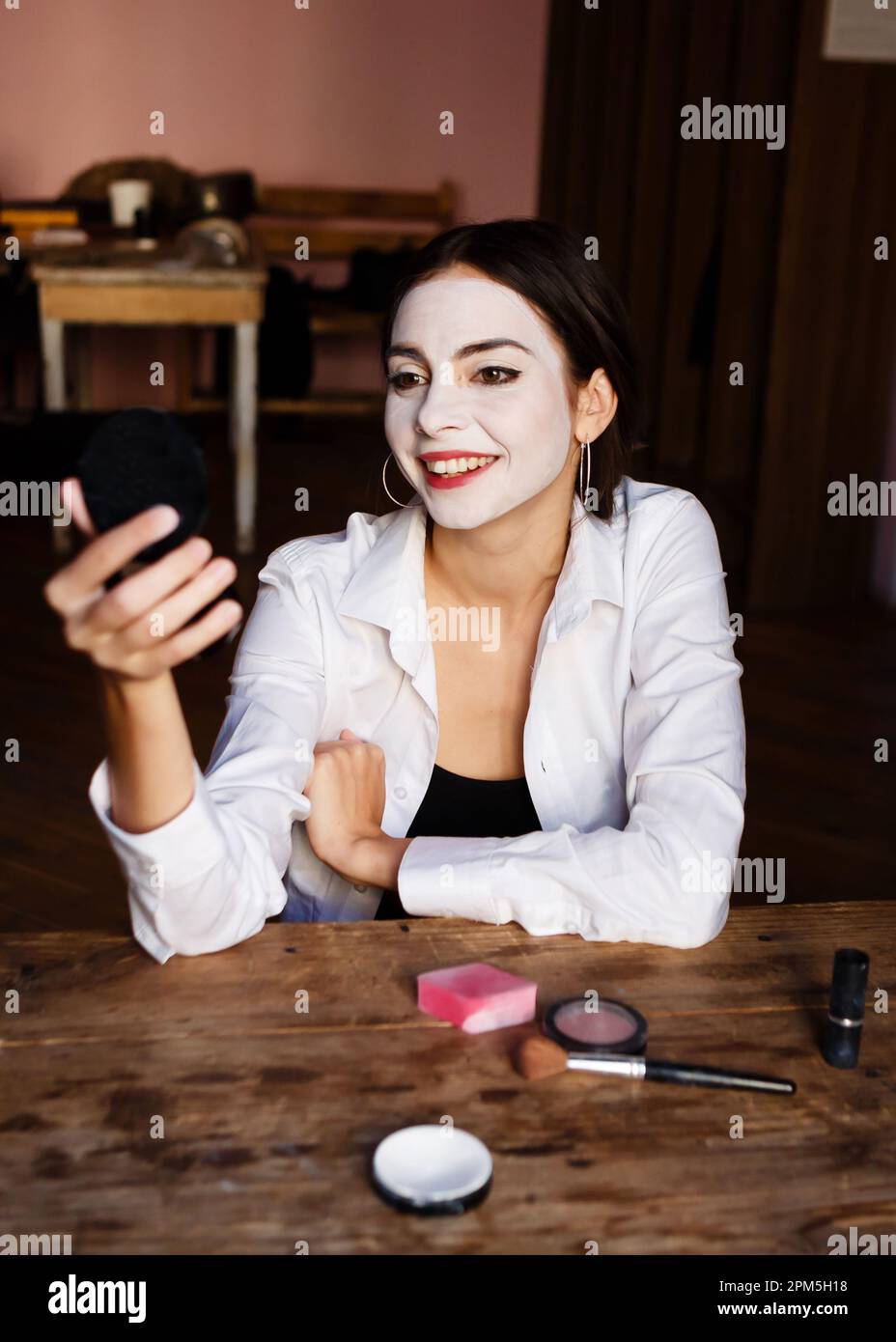 actress applies makeup to her face while sitting at rehearsal theater ...