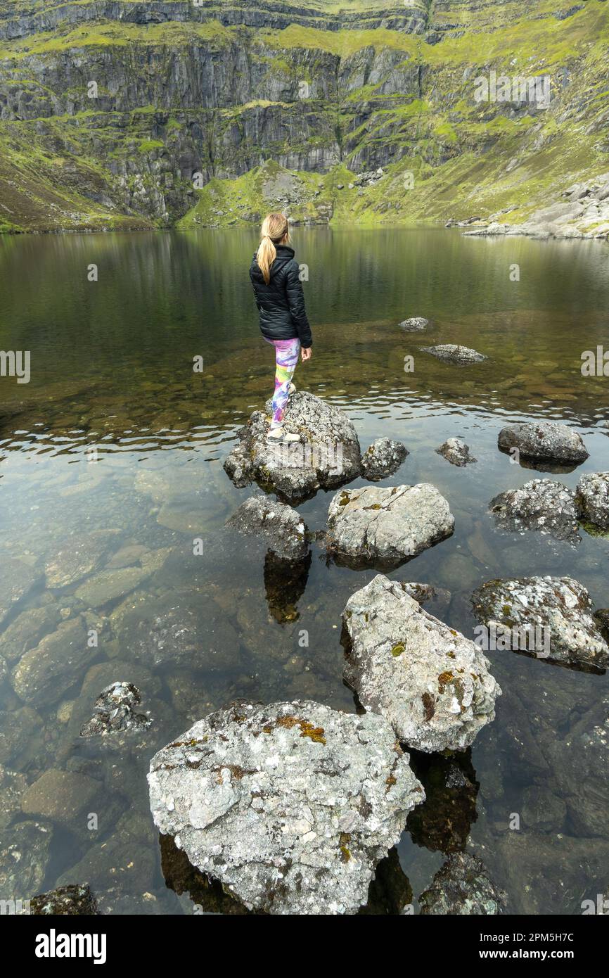 Woman mountaineer admiring the Coumshingaun lake Stock Photo - Alamy