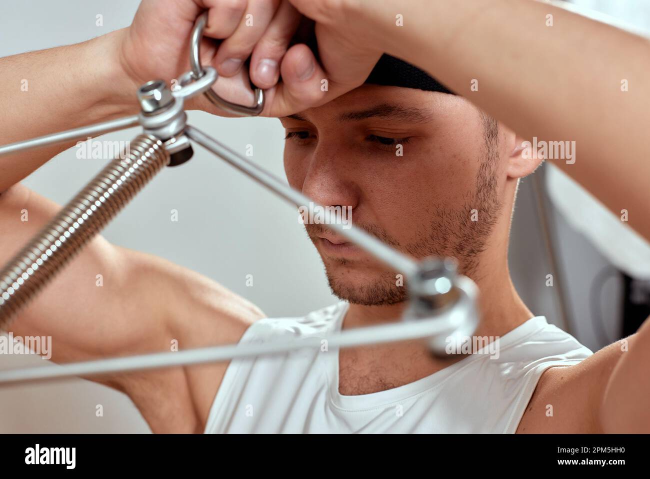 A man does exercises for the neck on reformers during Pilates, a young ...