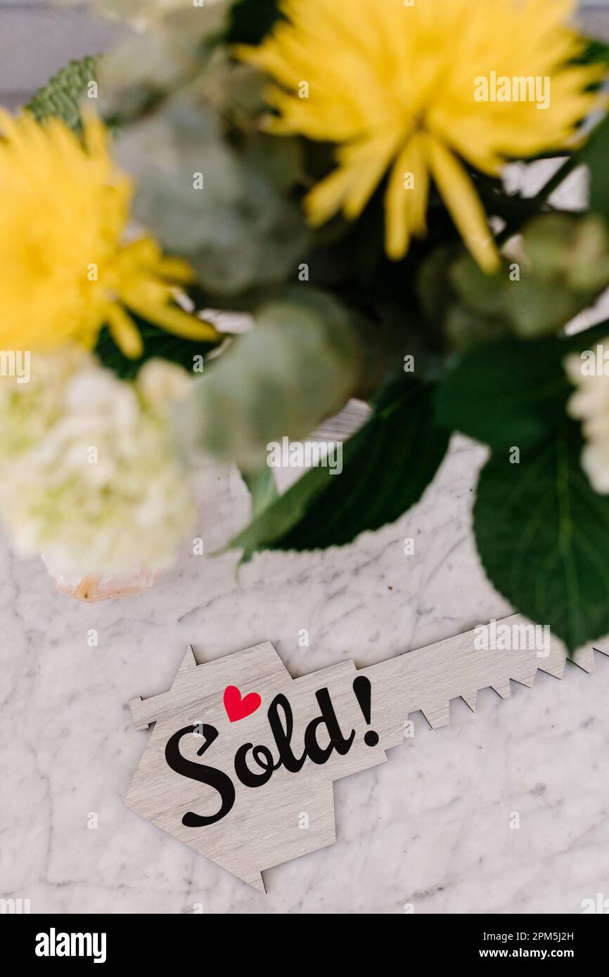House key shaped sold sign with yellow flowers Stock Photo - Alamy