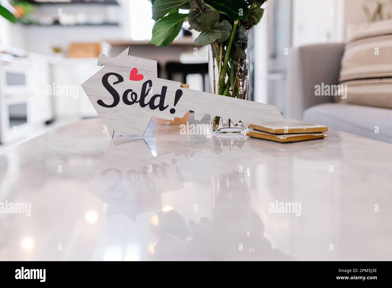 House Sold sign shaped as a key sitting on marble table Stock Photo - Alamy