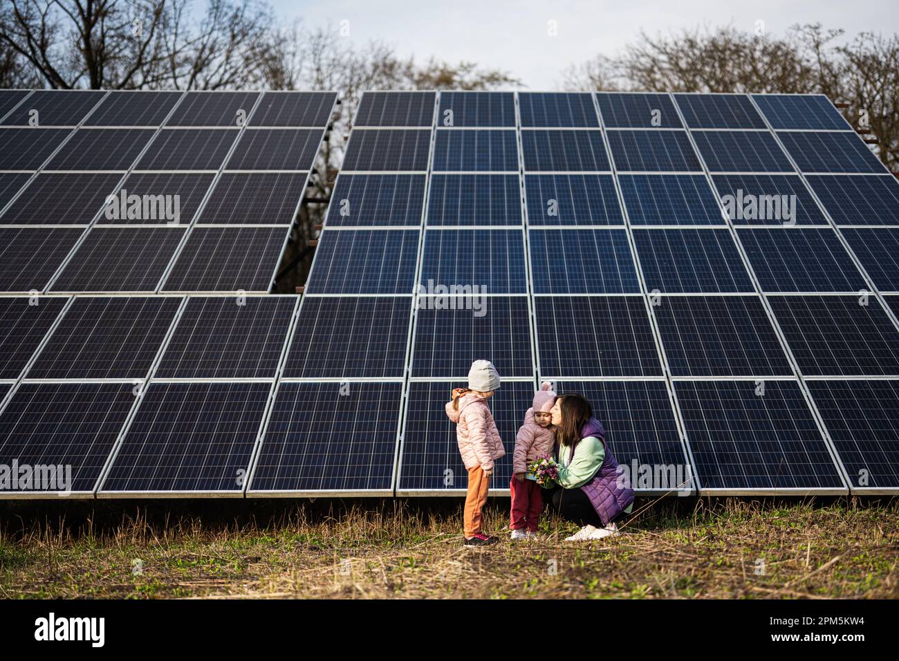 Mother with two daughters on the background of solar panels. Eco energy ...
