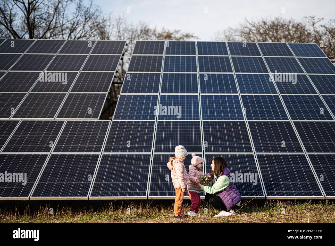 Mother with two daughters on the background of solar panels. Eco energy ...