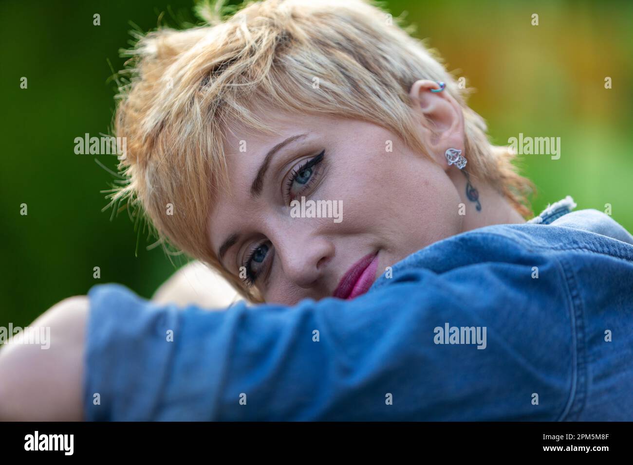 Gently resting on her folded arms, a young woman with short blonde hair ...