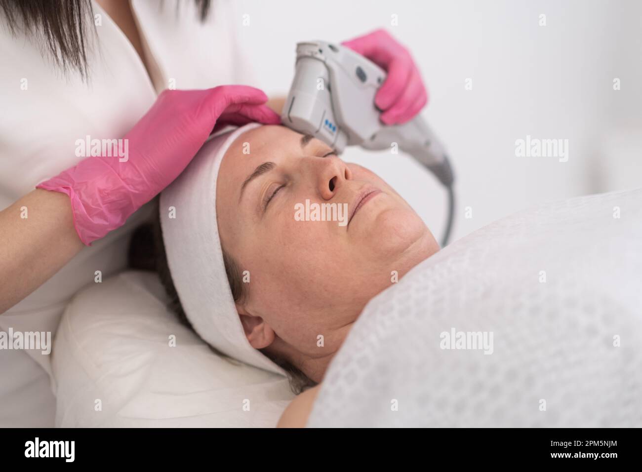 A woman face close up receiving a facial laser treatment to enhance her ...