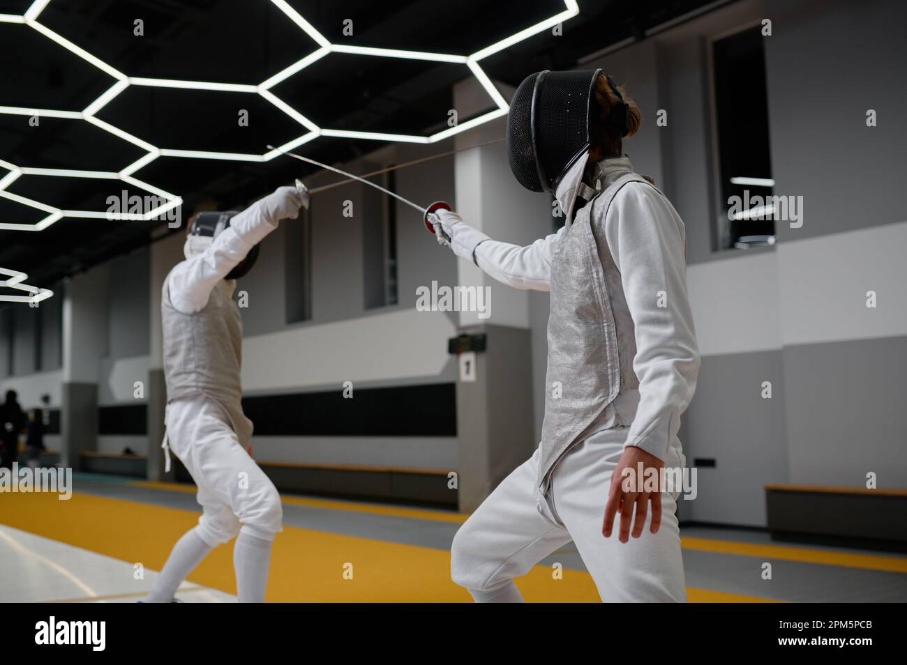 Athletes in uniforms and protective helmet mask fighting duel with ...