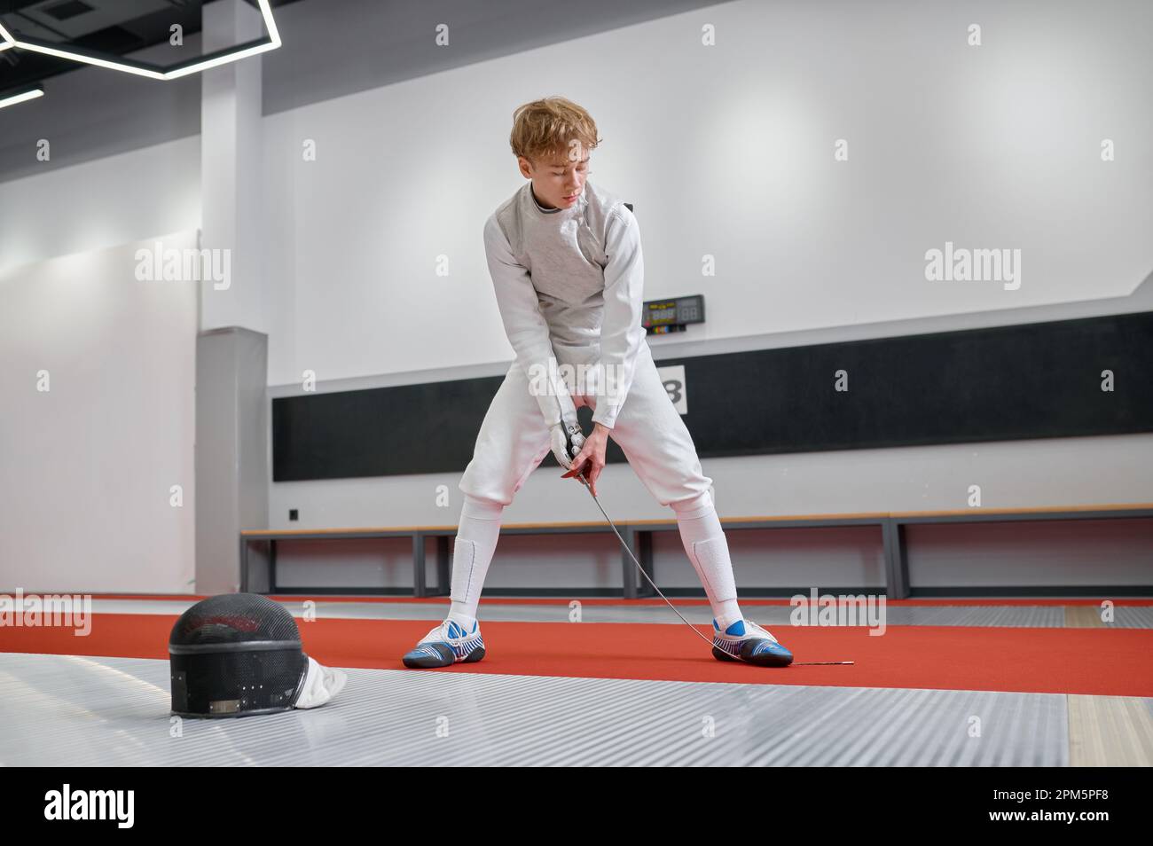 Teenage boy wearing fencing costume checking strength of blade Stock ...