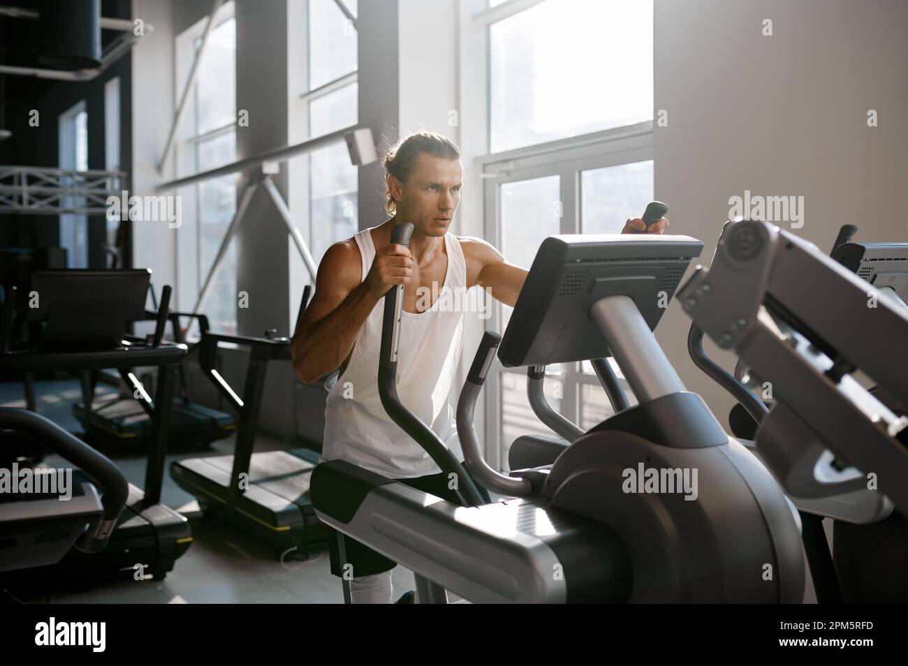 Sweaty sportsman doing cardio exercise on orbitrack training apparatus ...