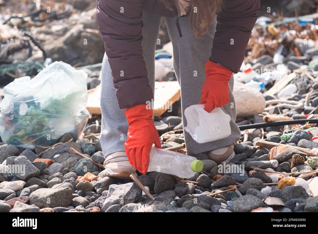 volunteer helping to clear away plastic, broken glass, and foam garbage ...