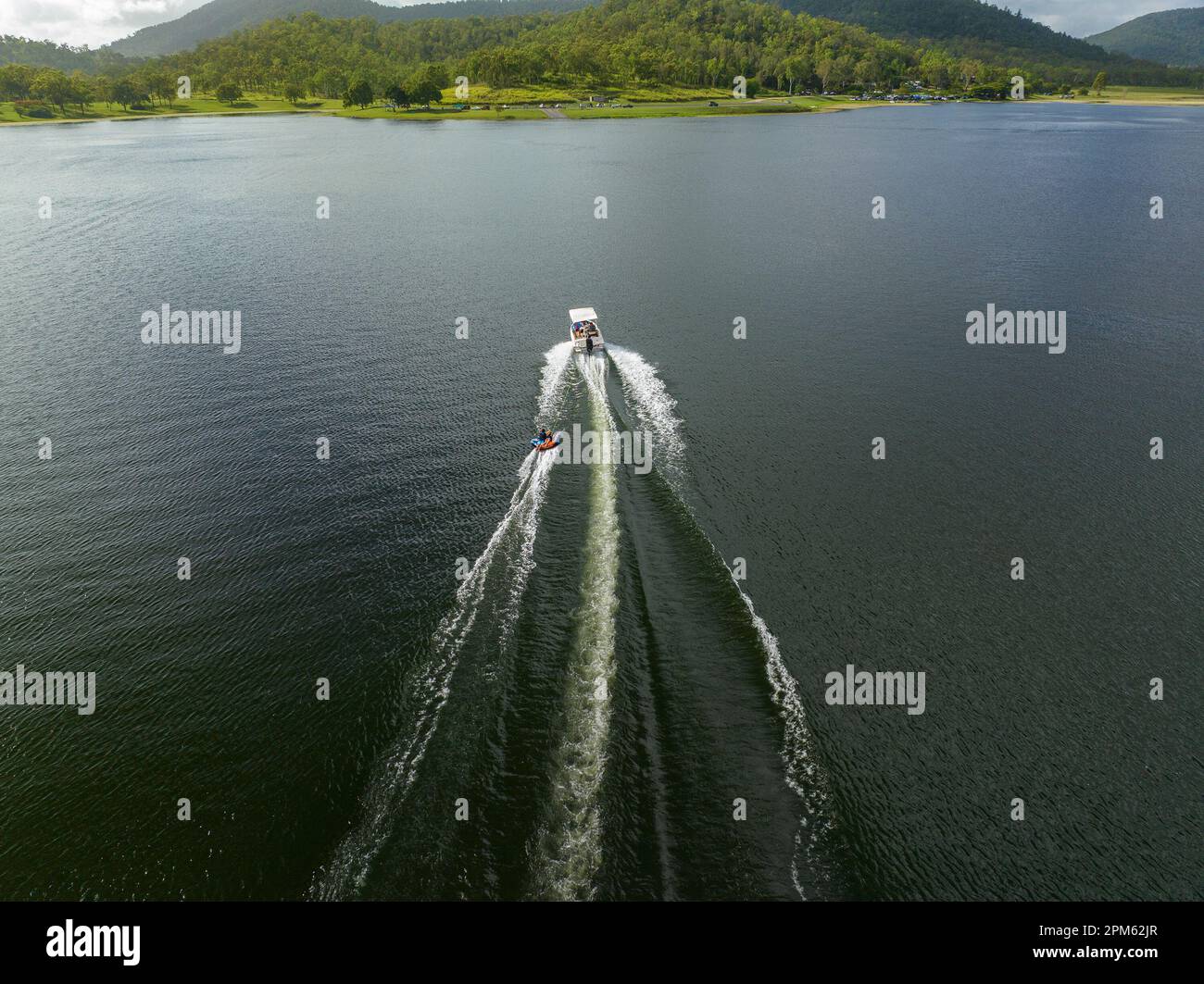 Drone aerial of a power boat pulling children on tubes across Kinchant ...