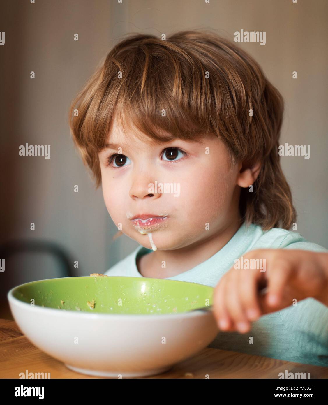 Happy child. The child in the kitchen at the table eating. Little baby ...