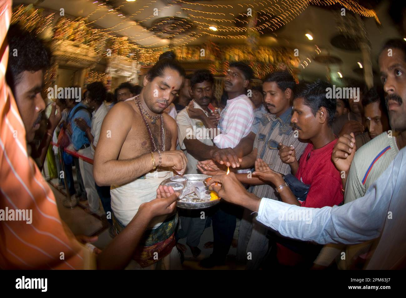 Priest passing around trays with holy flame for devotees during ...