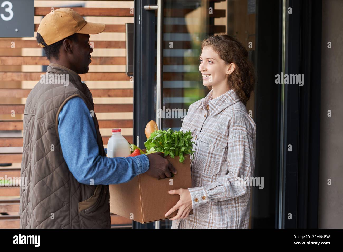 Side view portrait of smiling delivery man handing box with fresh ...