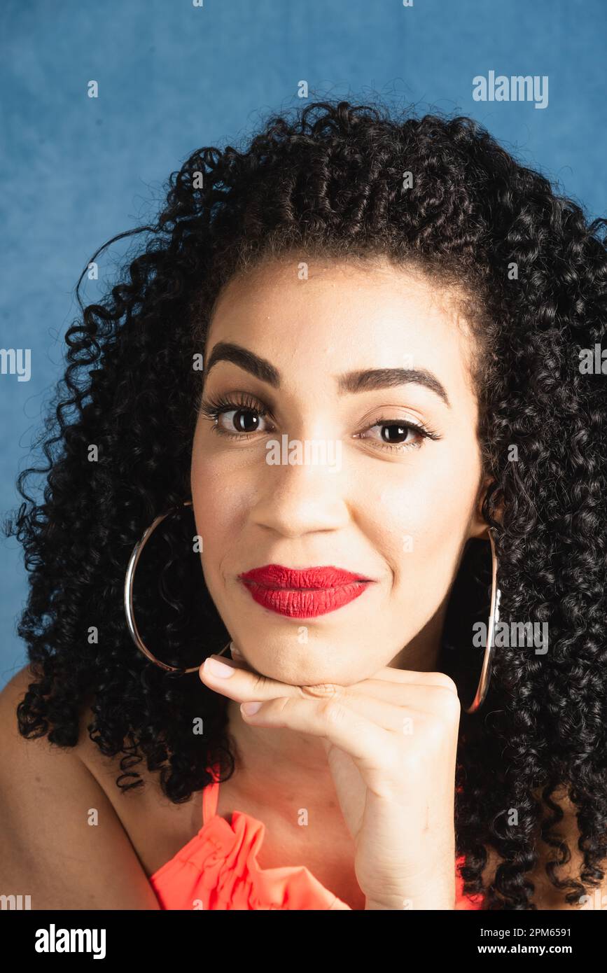 Close-up portrait of beautiful young woman with hand on chin against ...