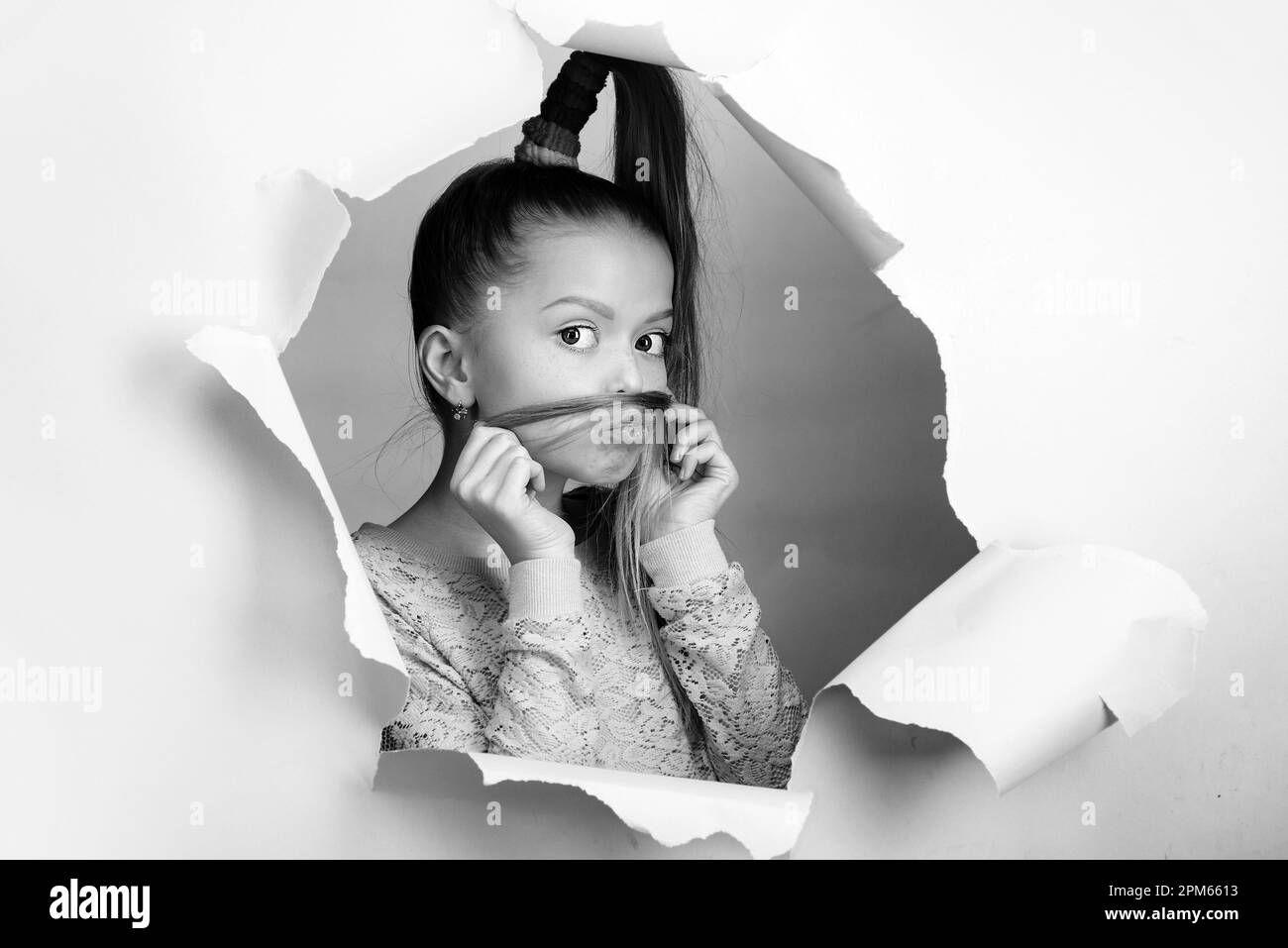 Funny kid girl looking out of a paper hole. Banner. Funny kid looks up ...