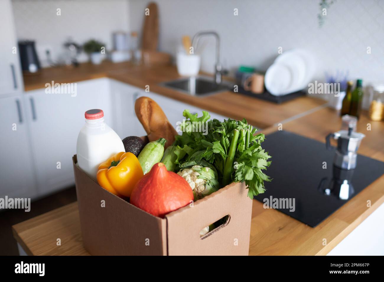 Background image of box with fresh groceries on table in modern kitchen ...