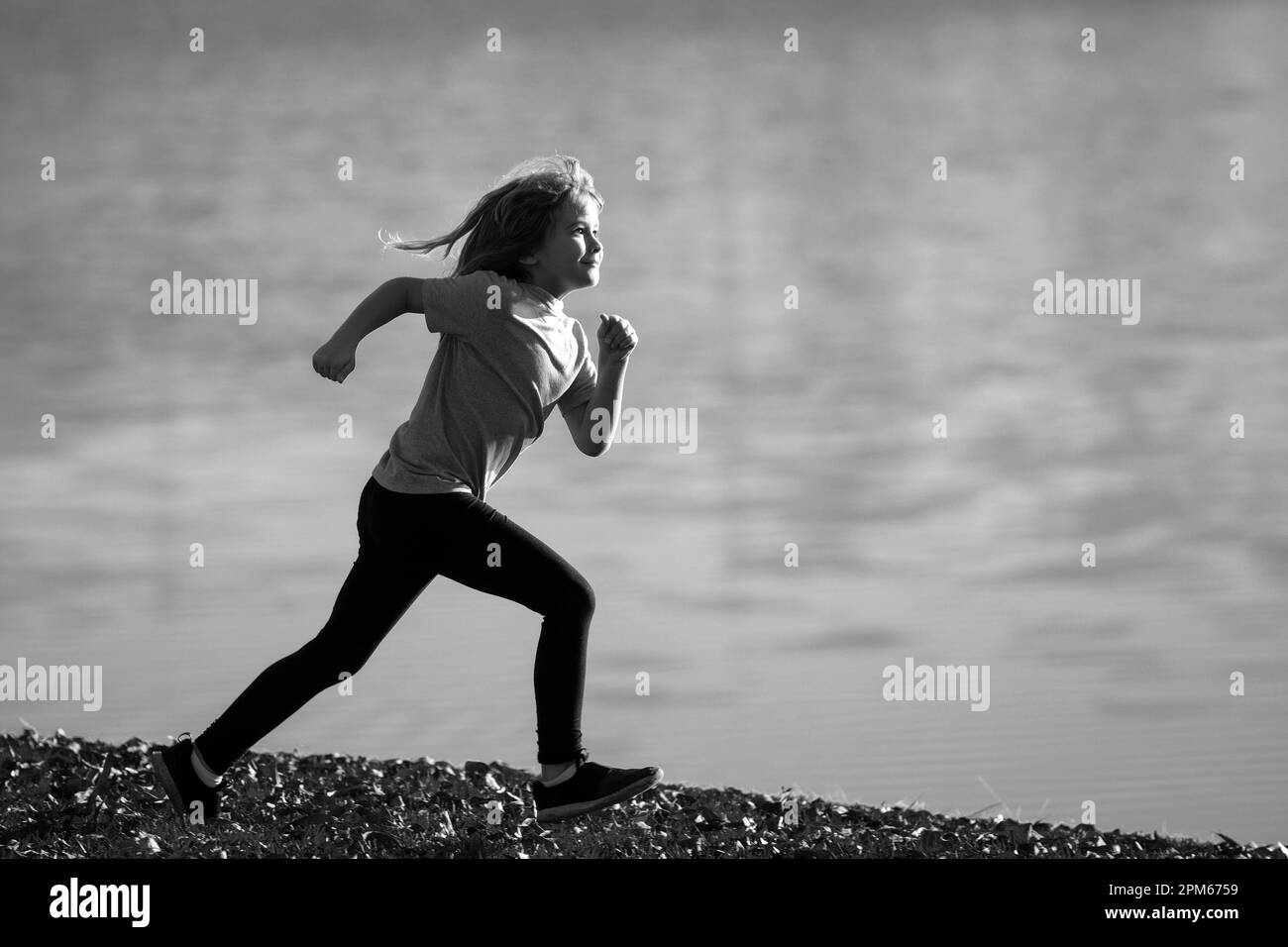 Child running through water close to shore along the lake. Sporty young ...