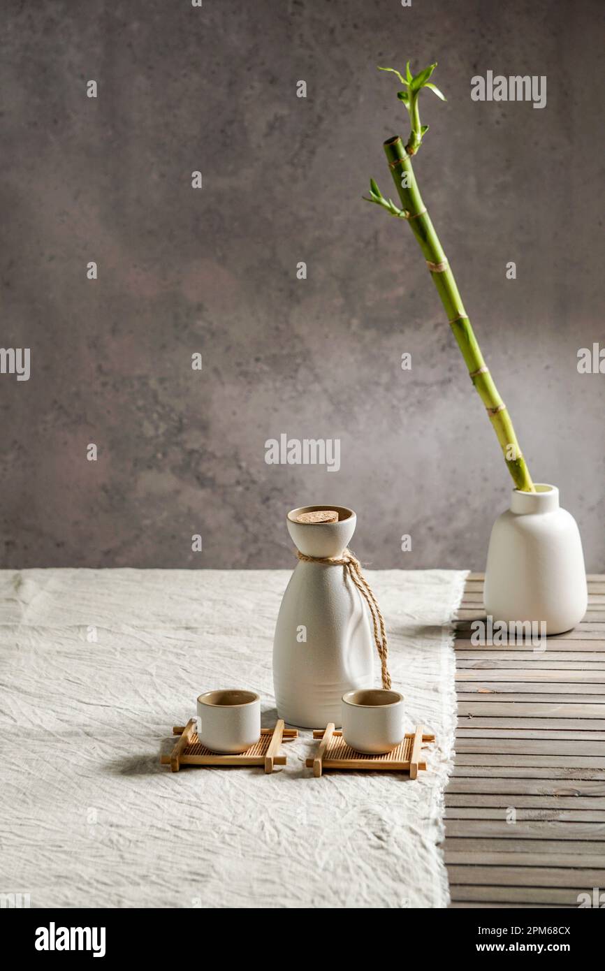 Japanese sake still life with a sprig of bamboo, light linen background ...