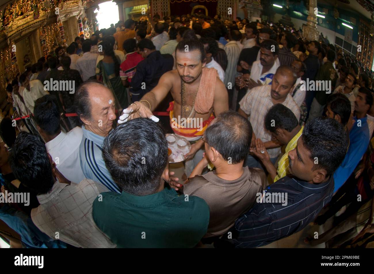 Priest applying white bindi on devotees at Deepavali ceremony, Sri ...