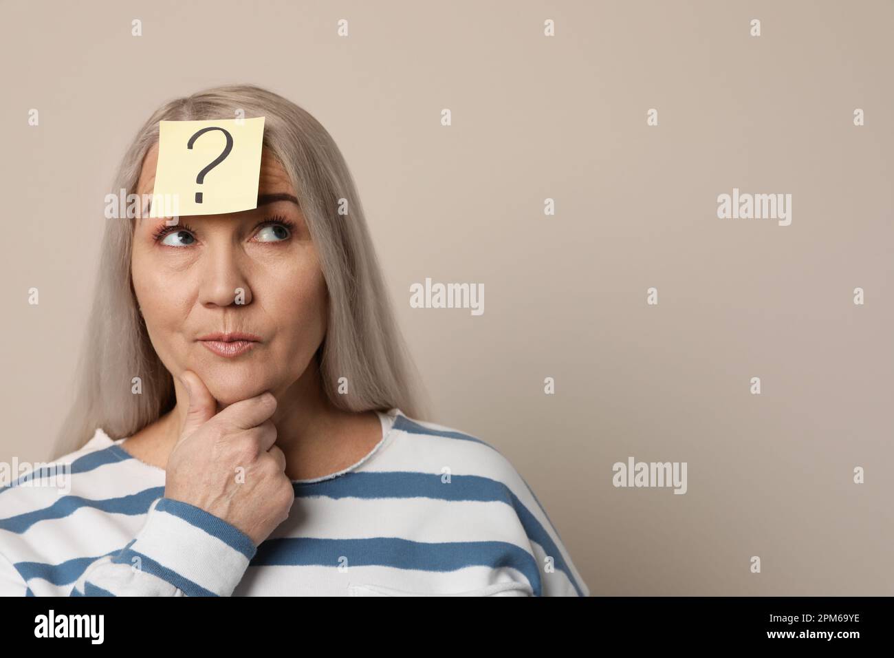Emotional mature woman with question mark on beige background. Space ...