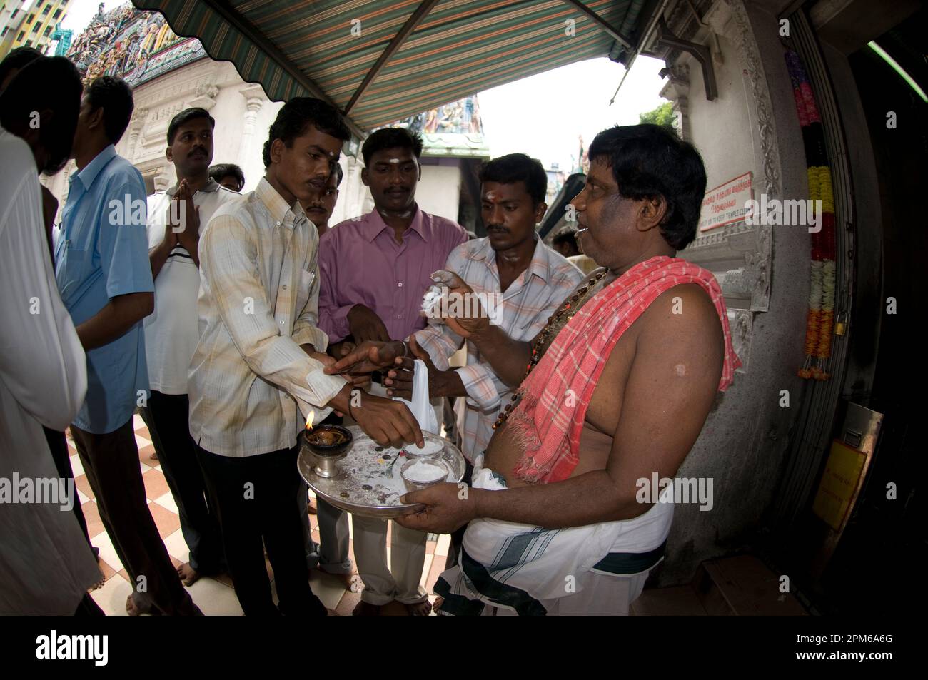 Priest with holy flame on tray and applying white bindi on devotees at ...