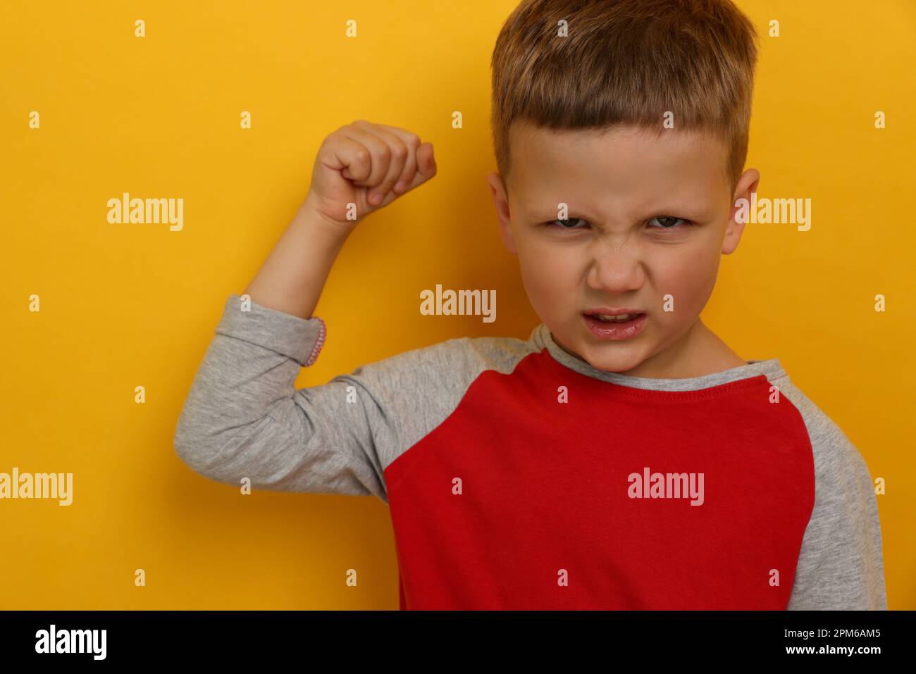 Angry little boy on yellow background. Aggressive behavior Stock Photo ...