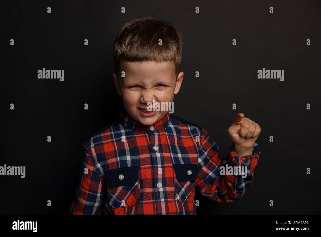 Angry little boy on black background. Aggressive behavior Stock Photo ...