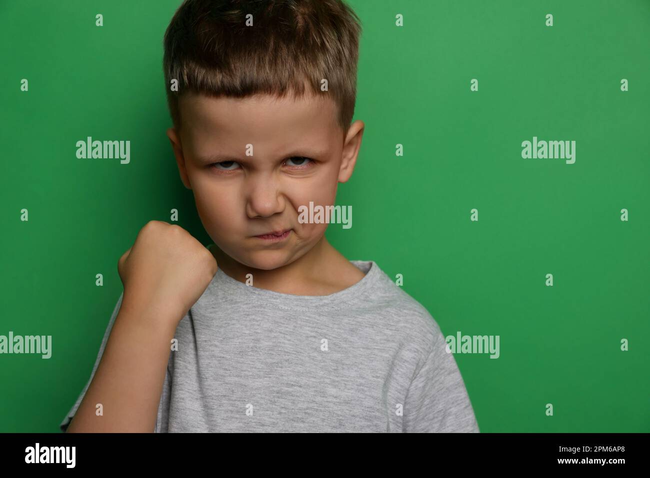 Angry little boy on green background, space for text. Aggressive ...