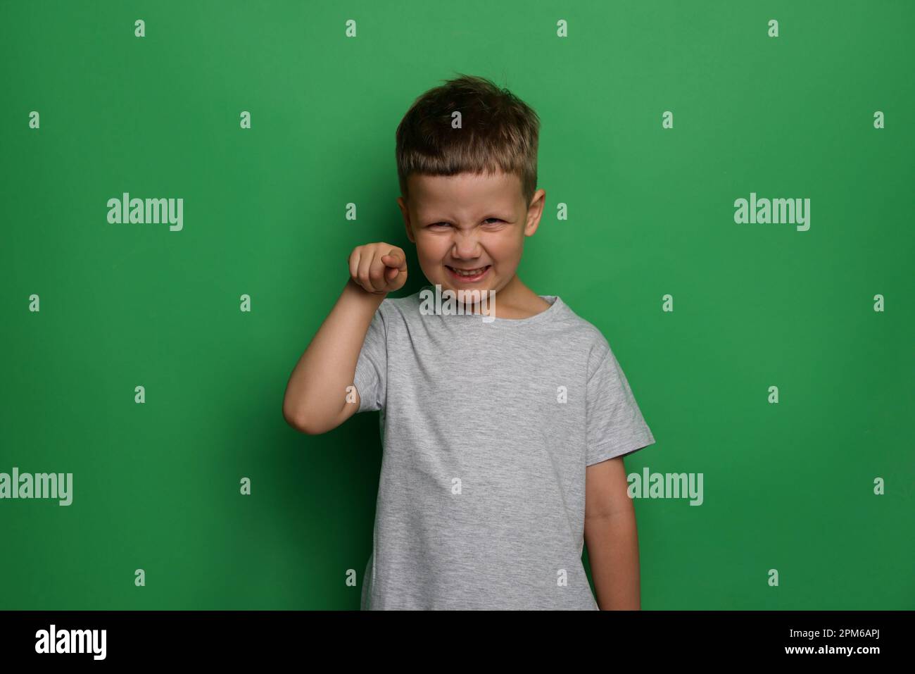 Angry little boy on green background. Aggressive behavior Stock Photo ...