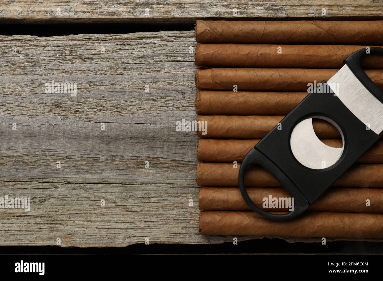 Cigars and guillotine cutter on wooden table, top view. Space for text ...