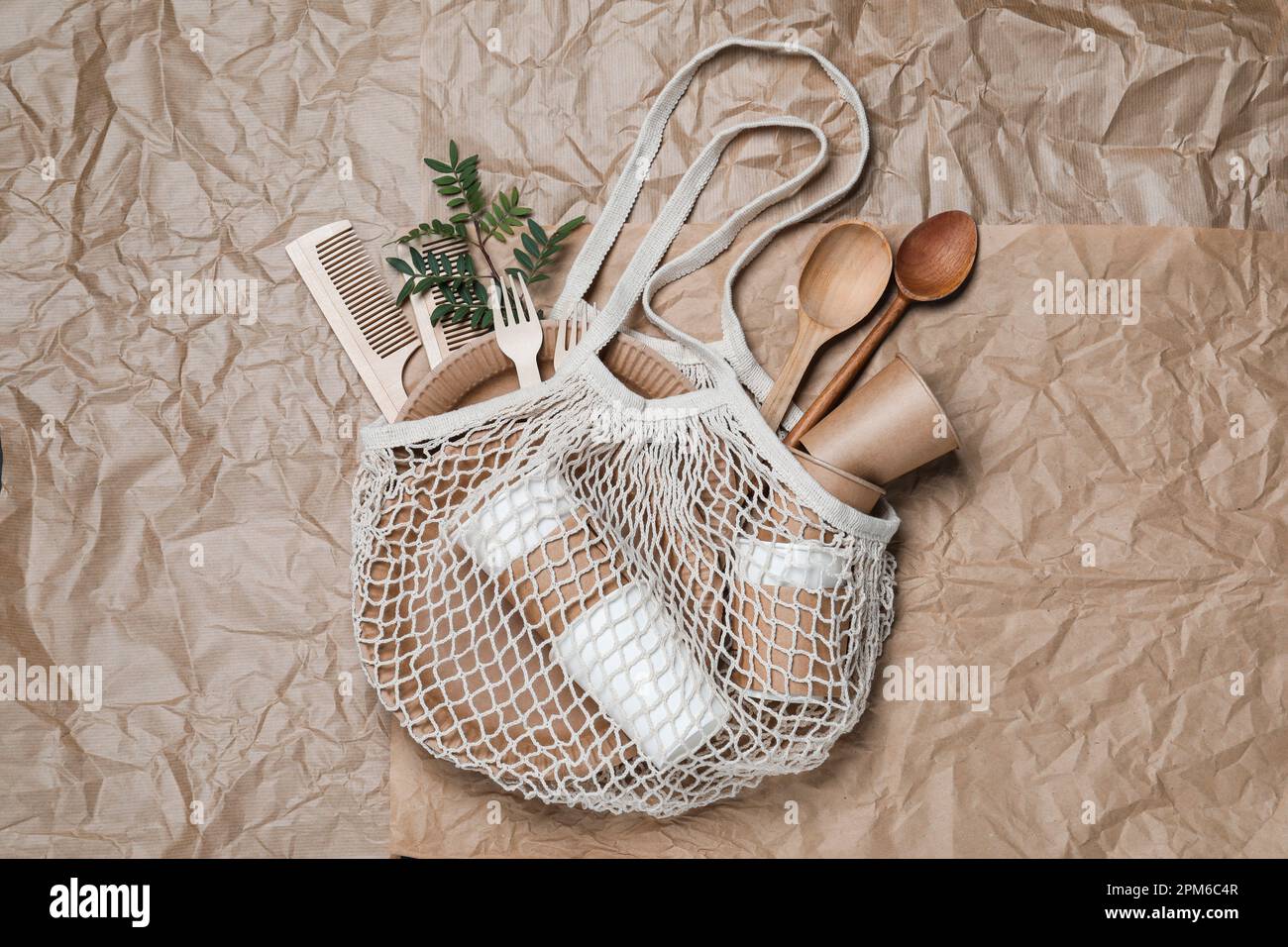 Net bag with different eco items on crumpled paper, top view. Recycling ...