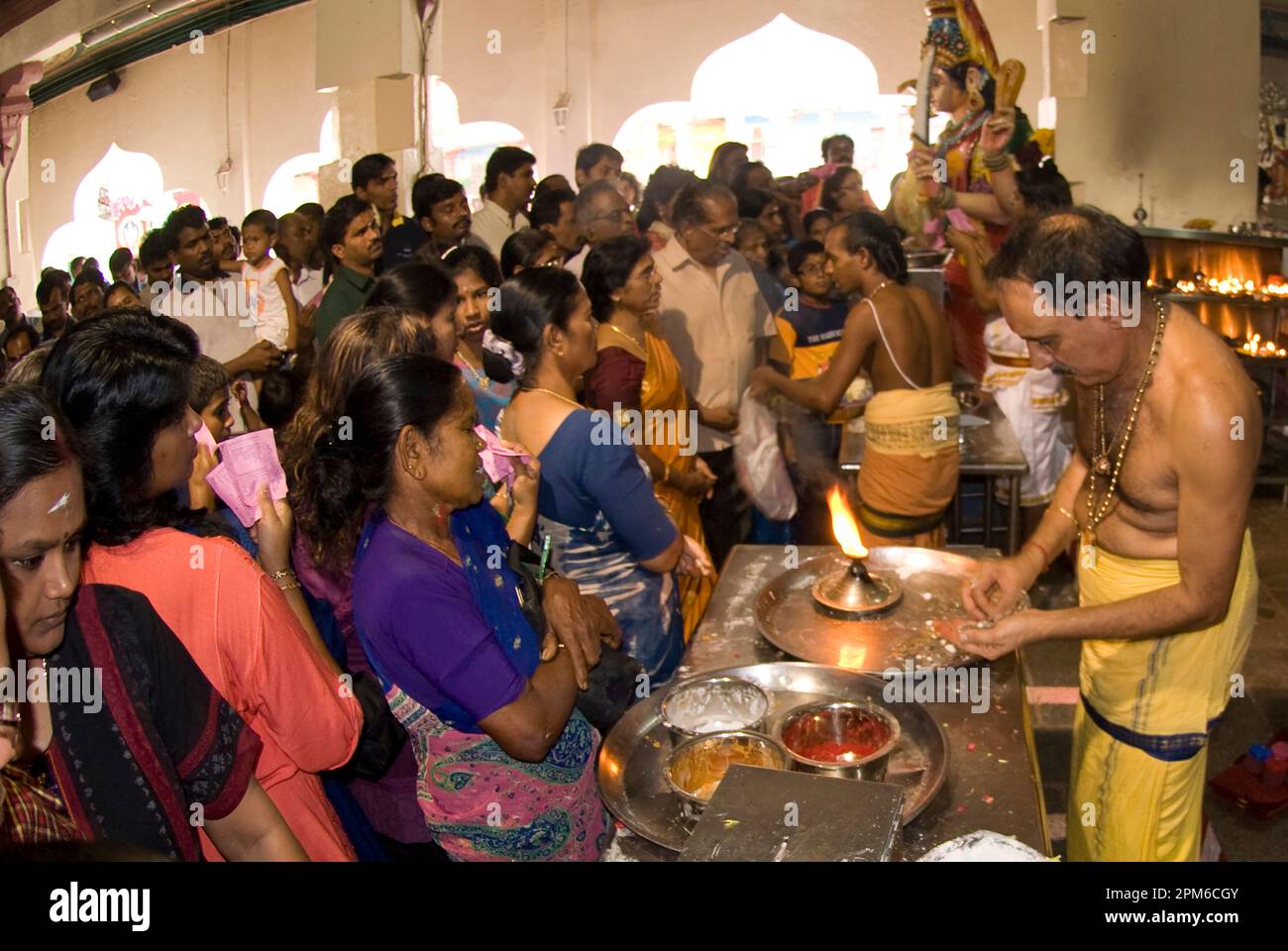 Devotees queueing to collect items from priests with holy flame at ...