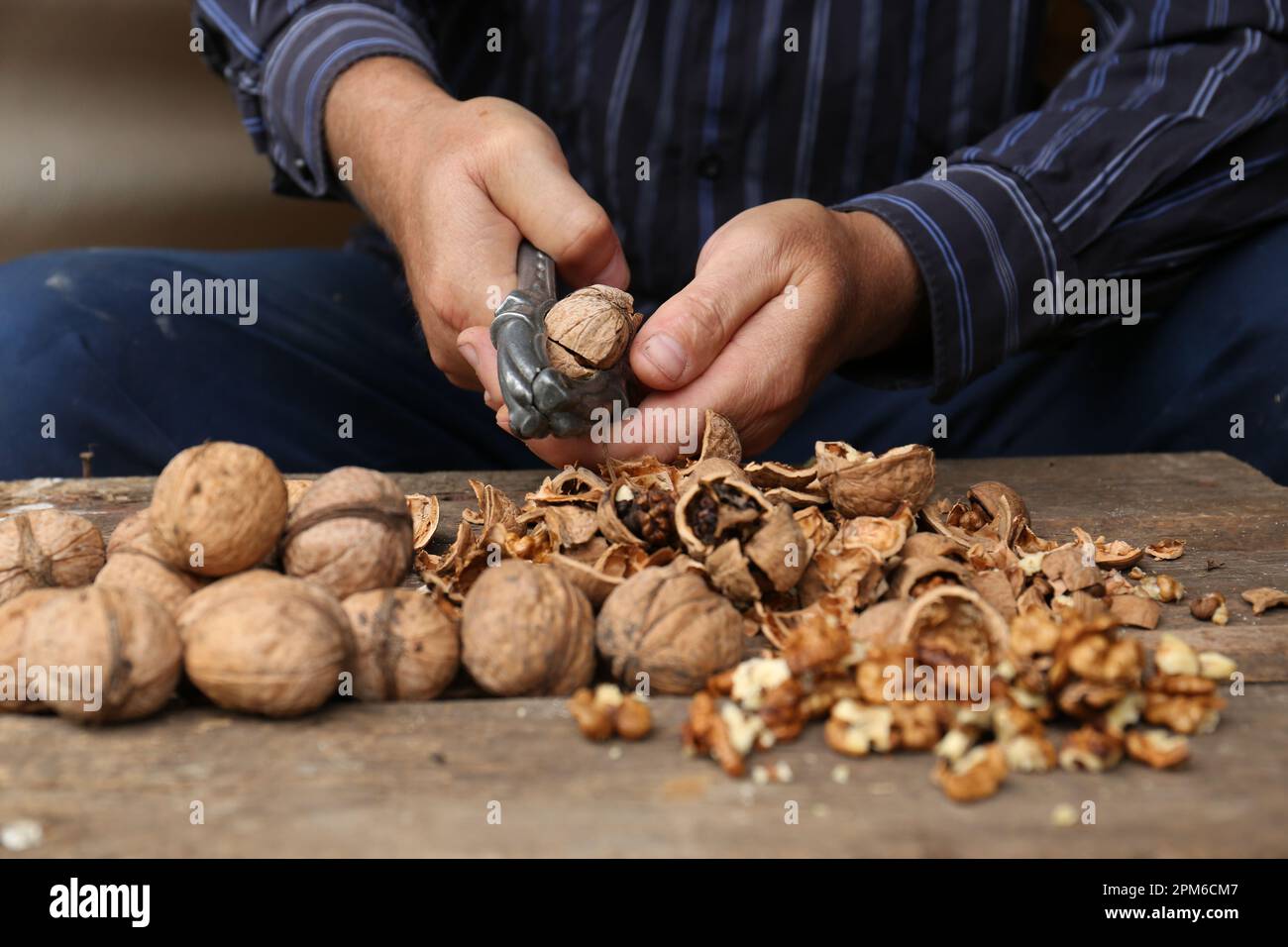 Man cracking walnuts at wooden table, closeup Stock Photo - Alamy