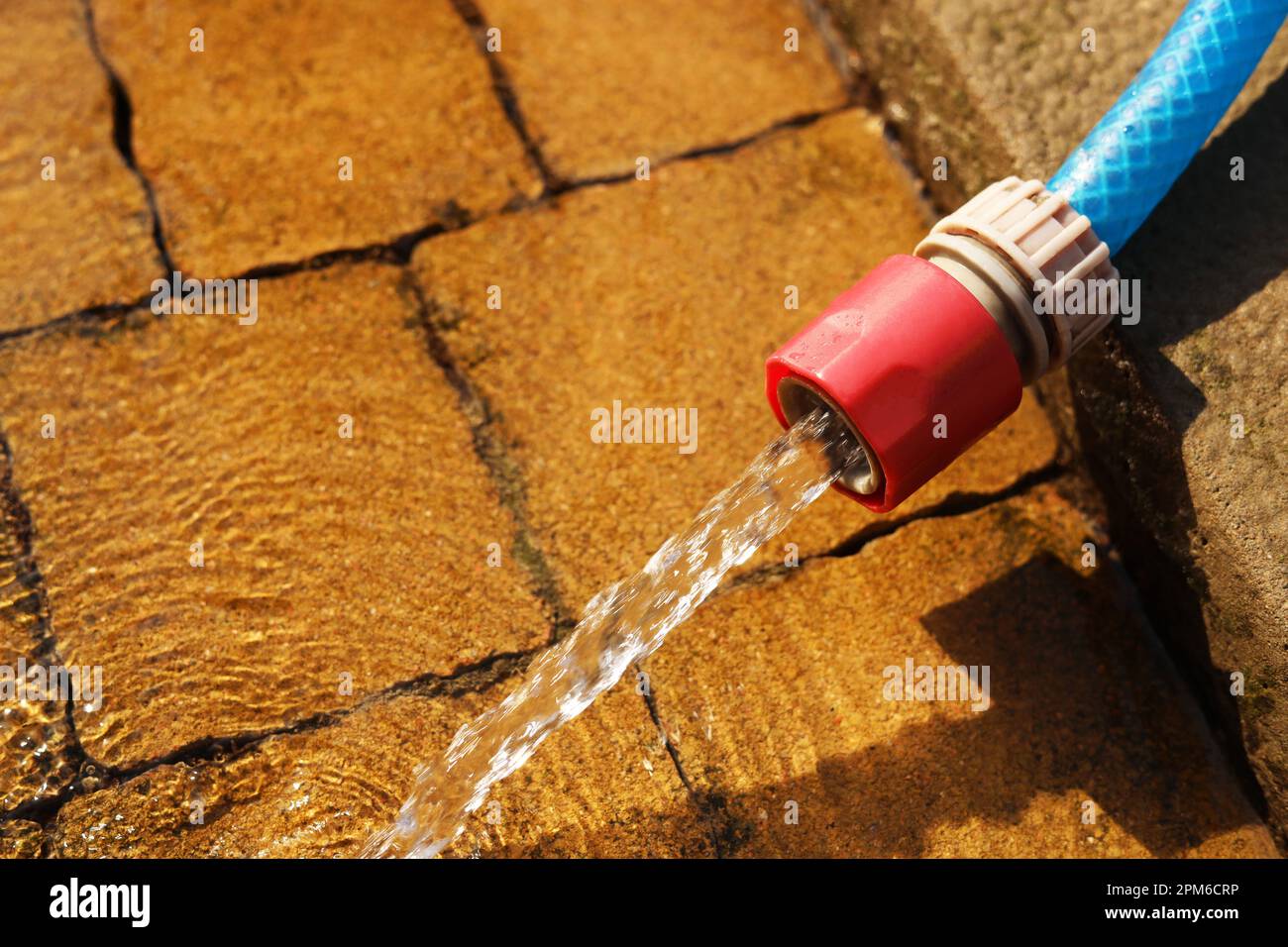 Water flowing from hose on stone floor outdoors, closeup. Space for ...