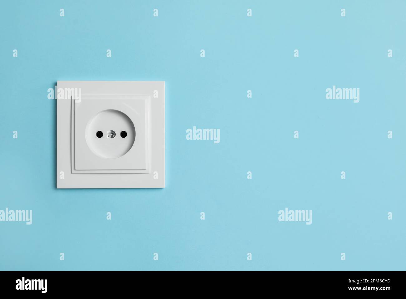 Power socket on light blue wall, space for text. Electrical supply ...