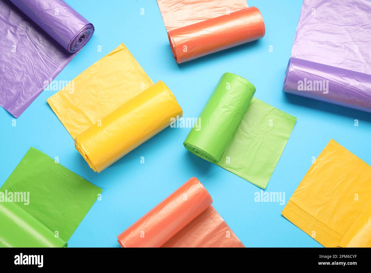 Rolls of different garbage bags on light blue background, flat lay ...