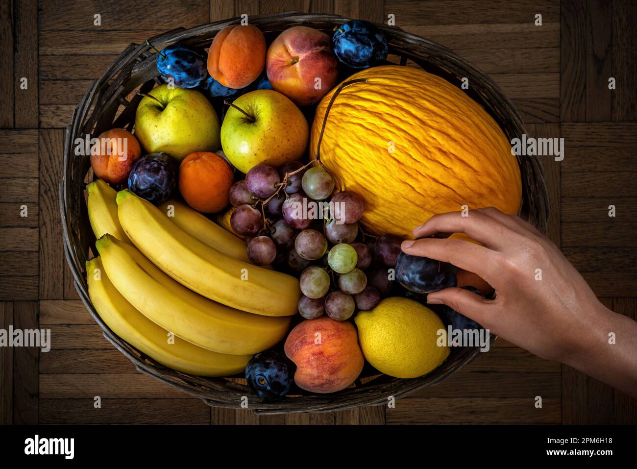 The human hand takes fruit from a basket. Top view Stock Photo - Alamy