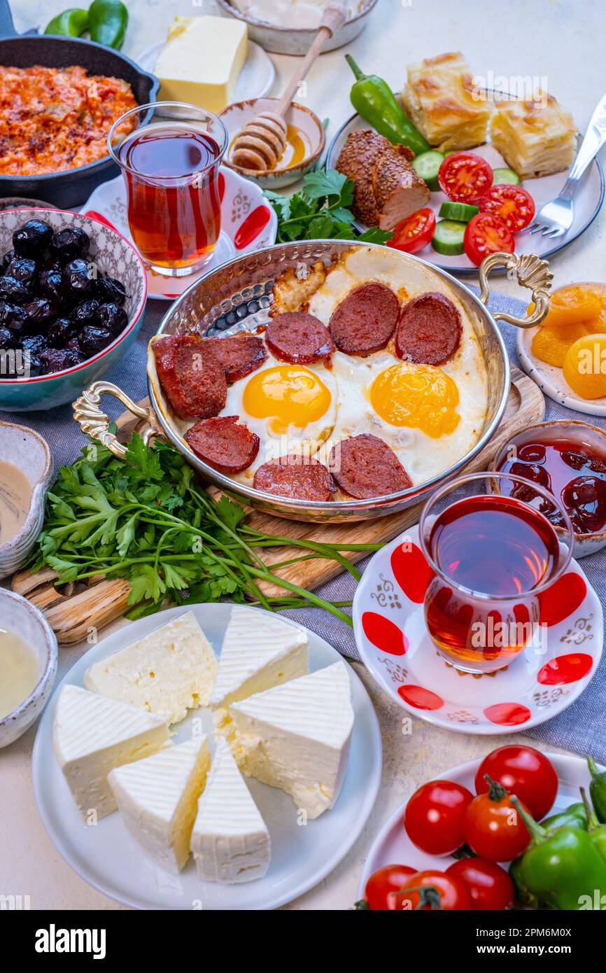 Turkish breakfast table from front view. Eggs and sujuk in a copper pan ...