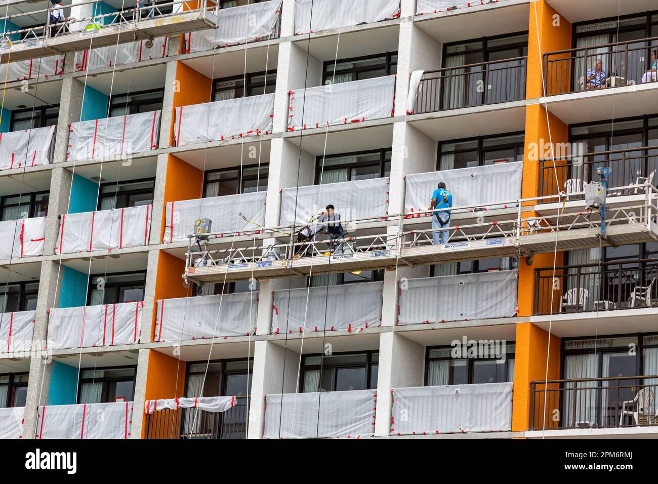 Men use a window cleaning platform to paint the Landmark Resort in ...