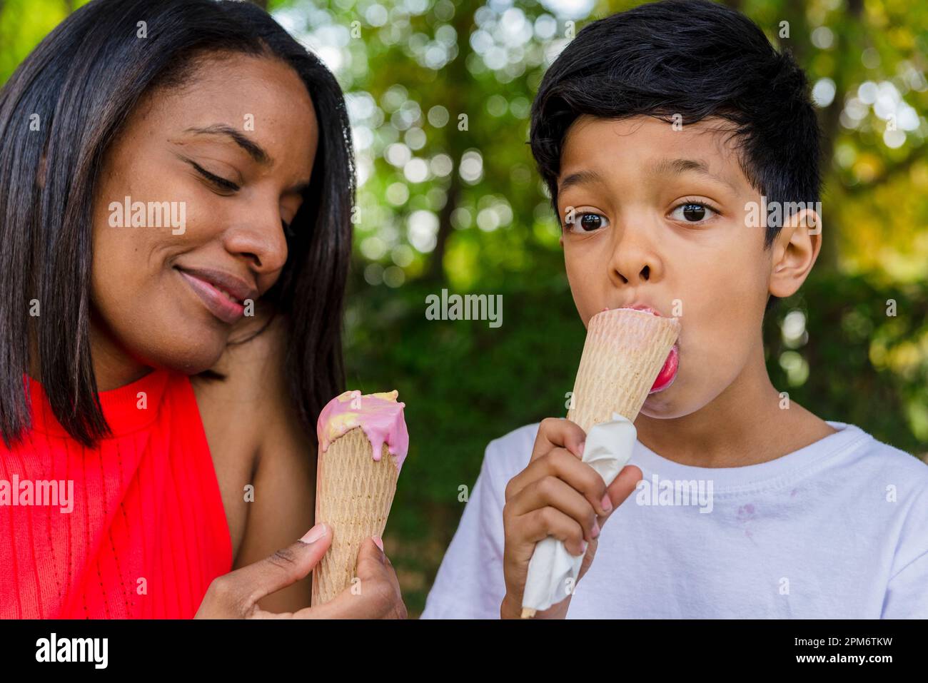 Mother and son enjoying eating ice-cream together outdoors in a park ...