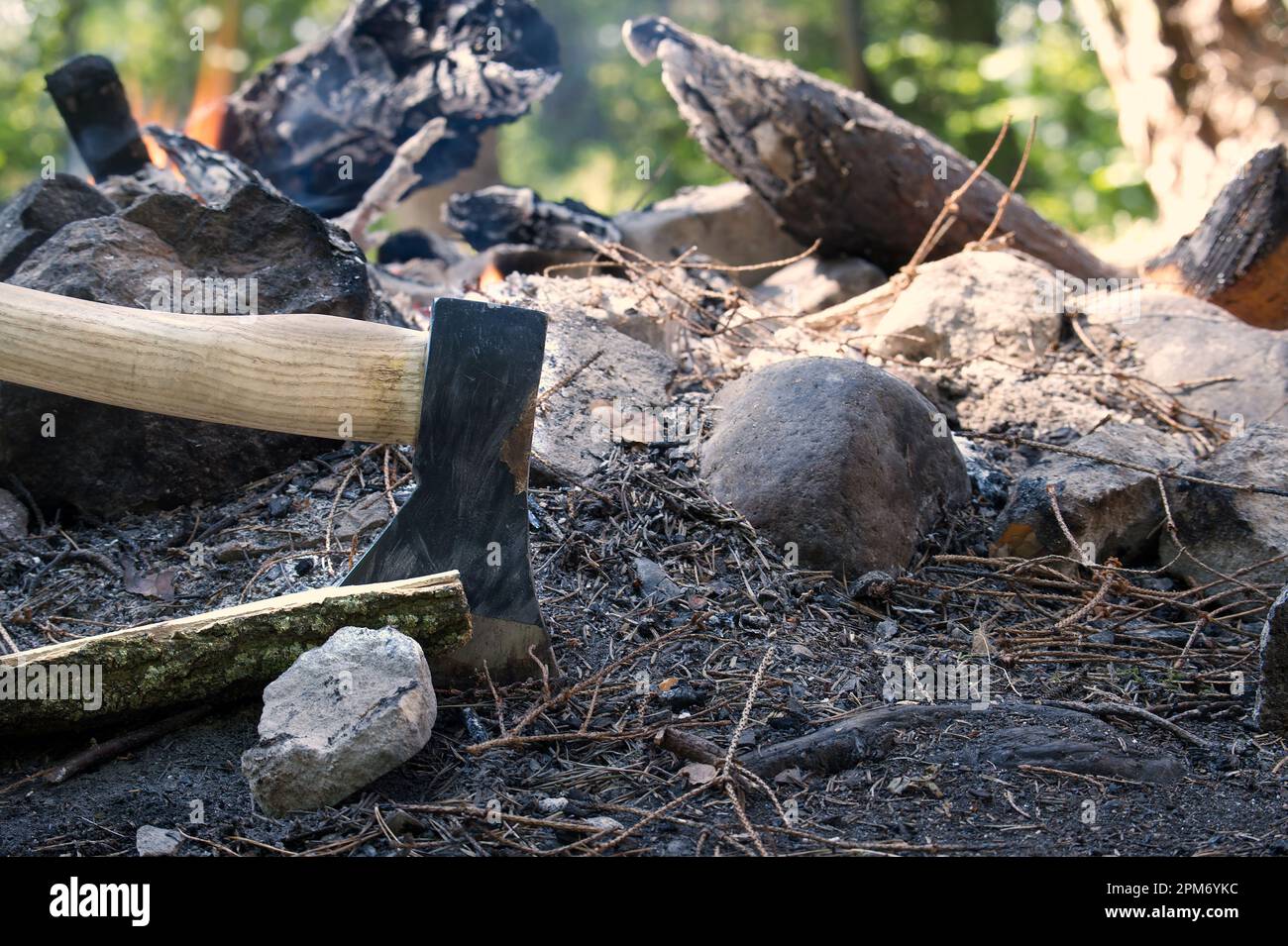 Camp fire in a forest with chopper lodged in a log of wood in the ...